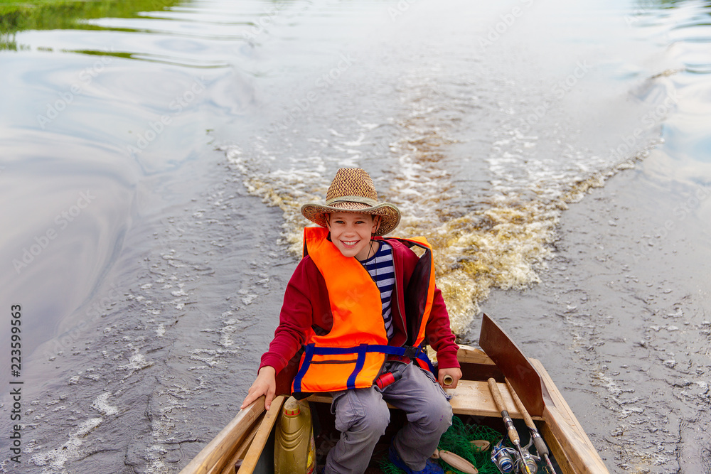 boy driving a motor boat. the child in a lifejacket goes fishing on a ...