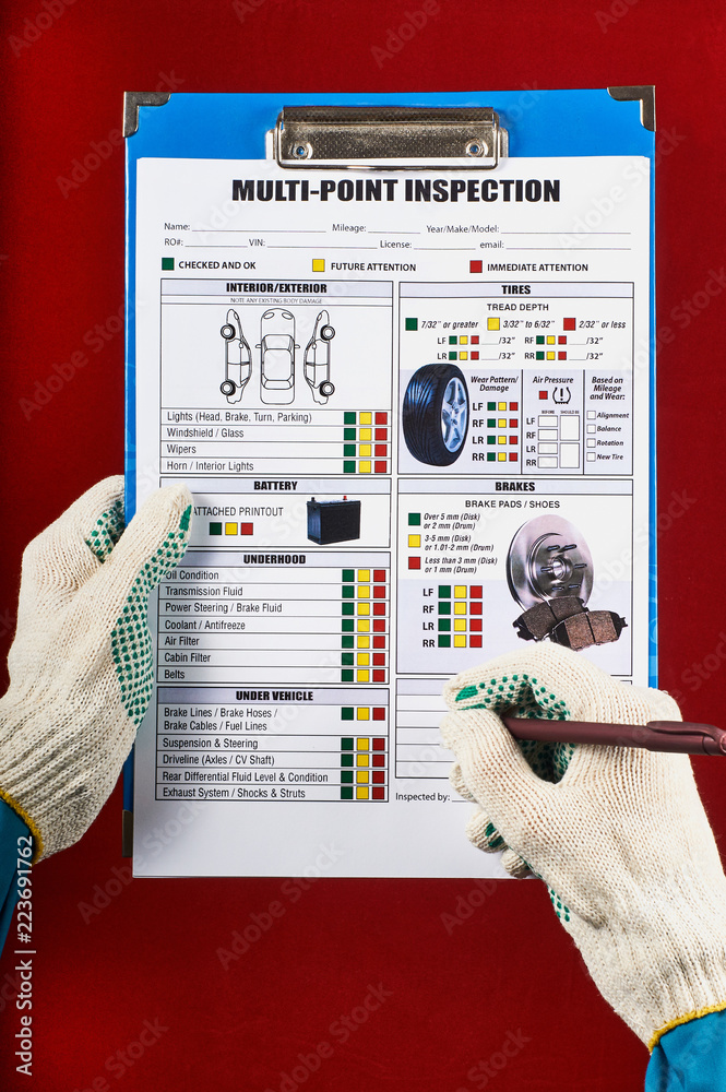 Mechanic writes in the vehicle multi-point inspection report form on a ...
