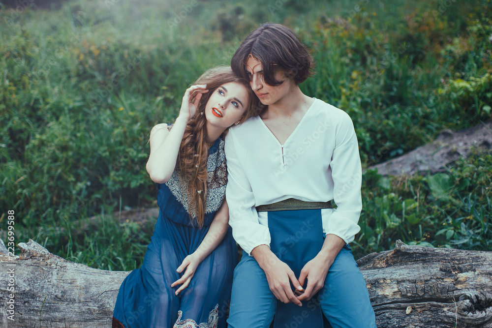 Young couple of elves in love siting on tree in magical forest outdoor ...