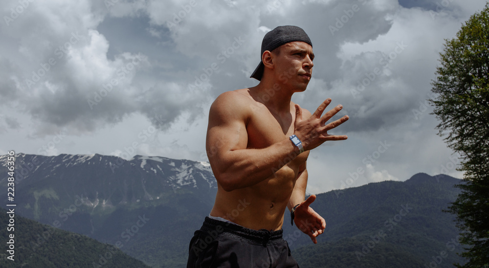 Young attractive tall muscular bodybuilder warming up before morning ...