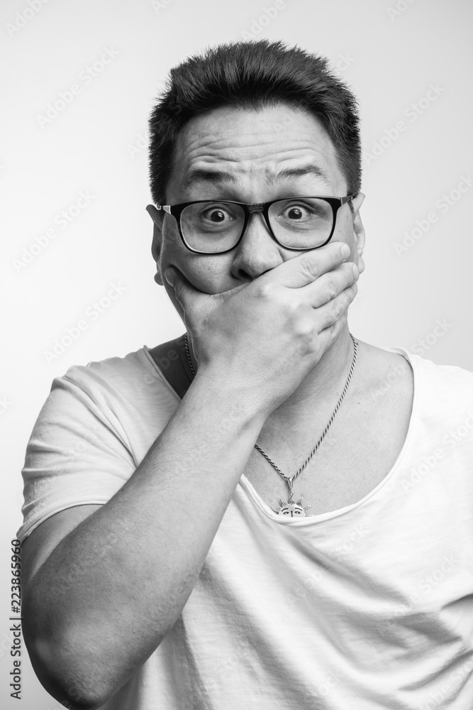 Portrait of shocked young man covering his mouth with hands, being ...