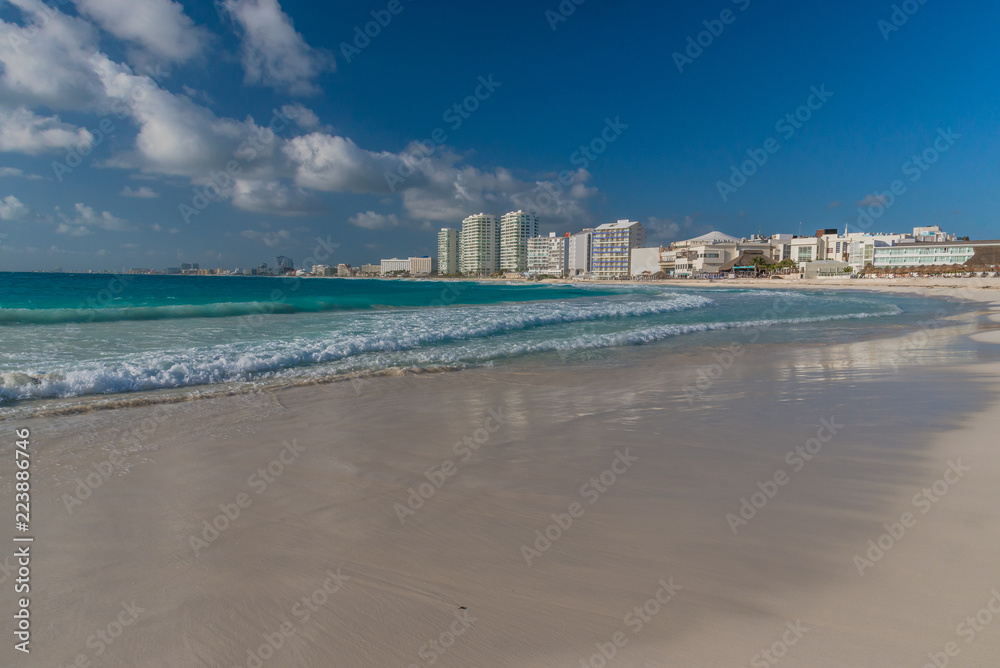 The gleaming white buildings of the Cancun Hotel Zone rise above sandy ...