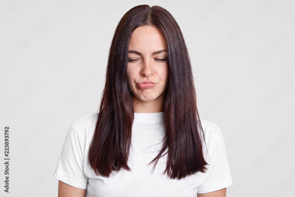 Displeased brunette young girl pouts lips, has discontent facial ...