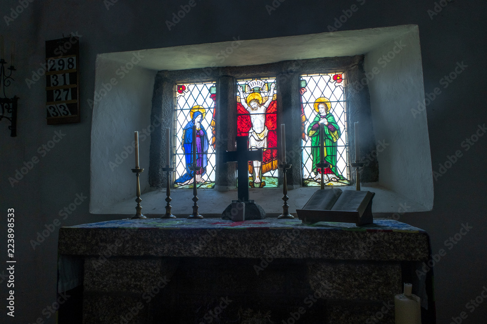Stained glass windows over an altar with candles in a medieval English ...