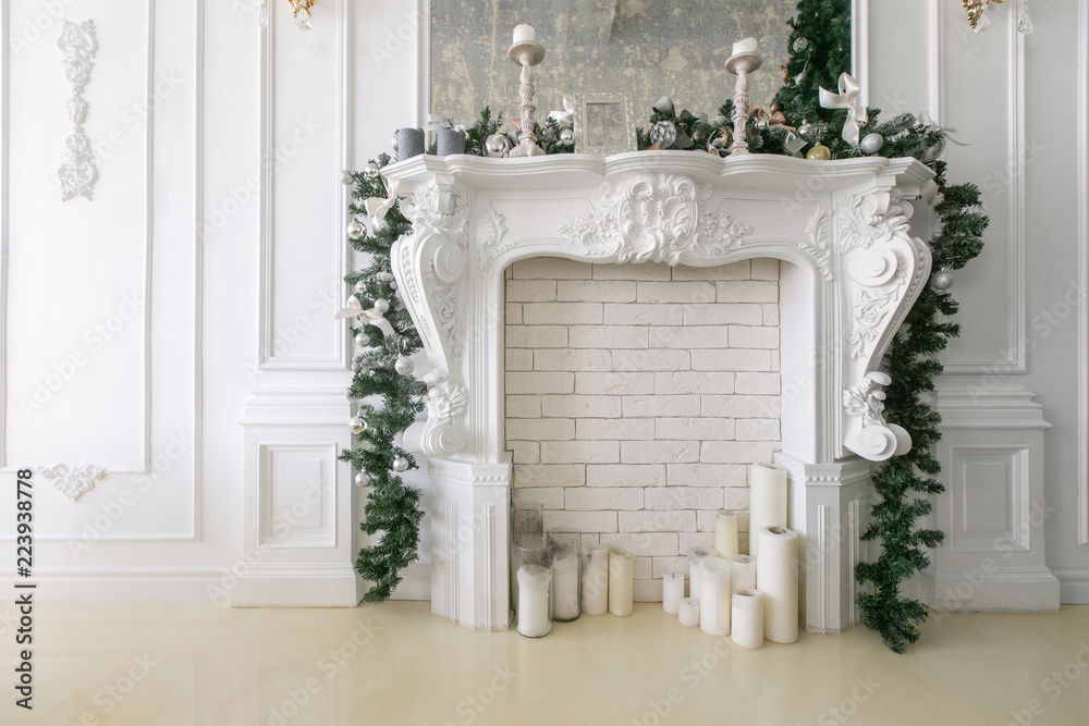 White fireplace decorated with candles and fir branches. Decorated ...