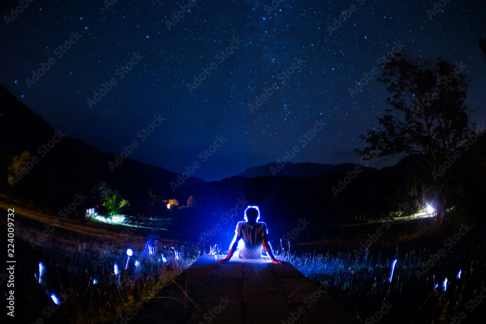 strange light in a dark forest at night. Silhouette of person standing ...