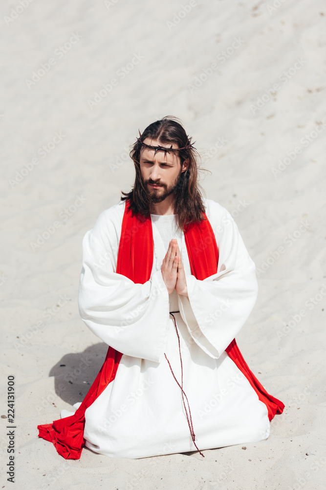 Jesus in robe, red sash and crown of thorns standing on knees and ...