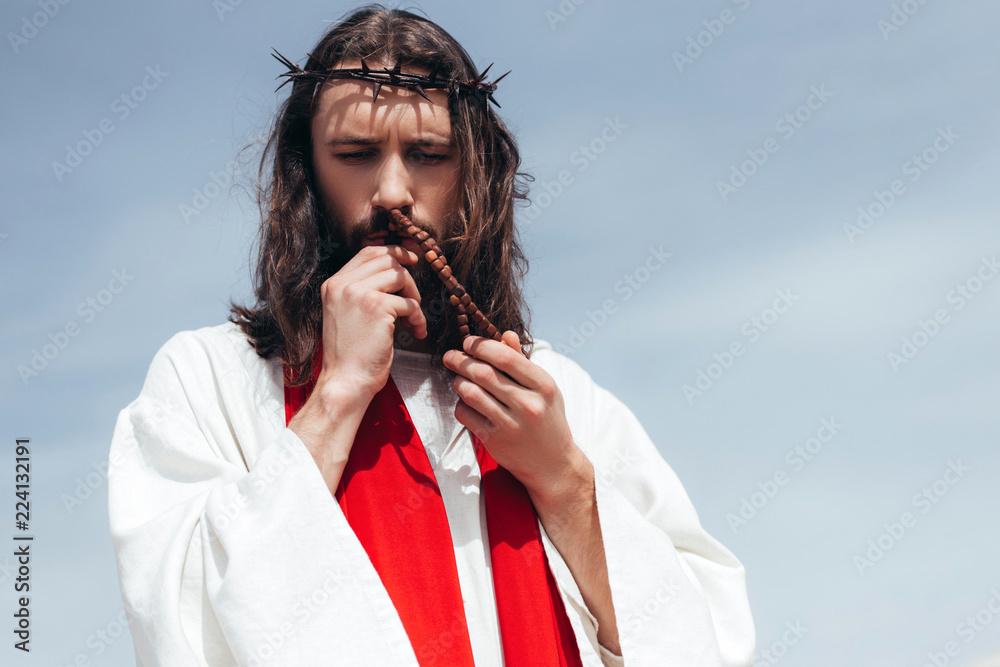 portrait of Jesus in robe, red sash and crown of thorns kissing rosary ...