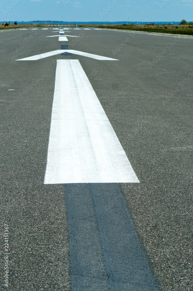 The markings of the runway. The white arrow painted on the pavement ...
