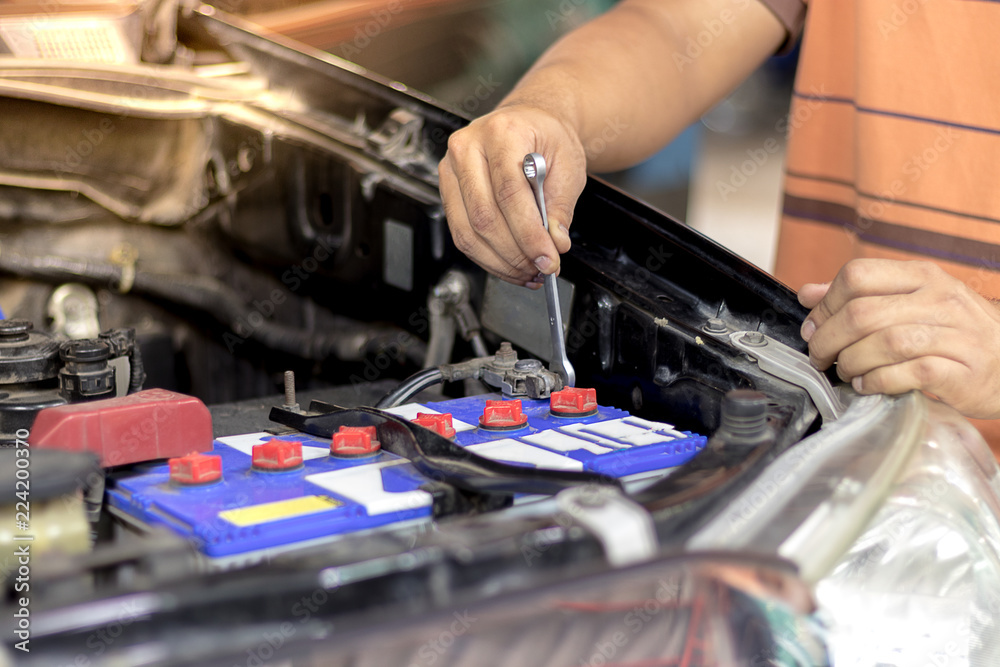A man are removing the battery terminals from the car to work on the ...