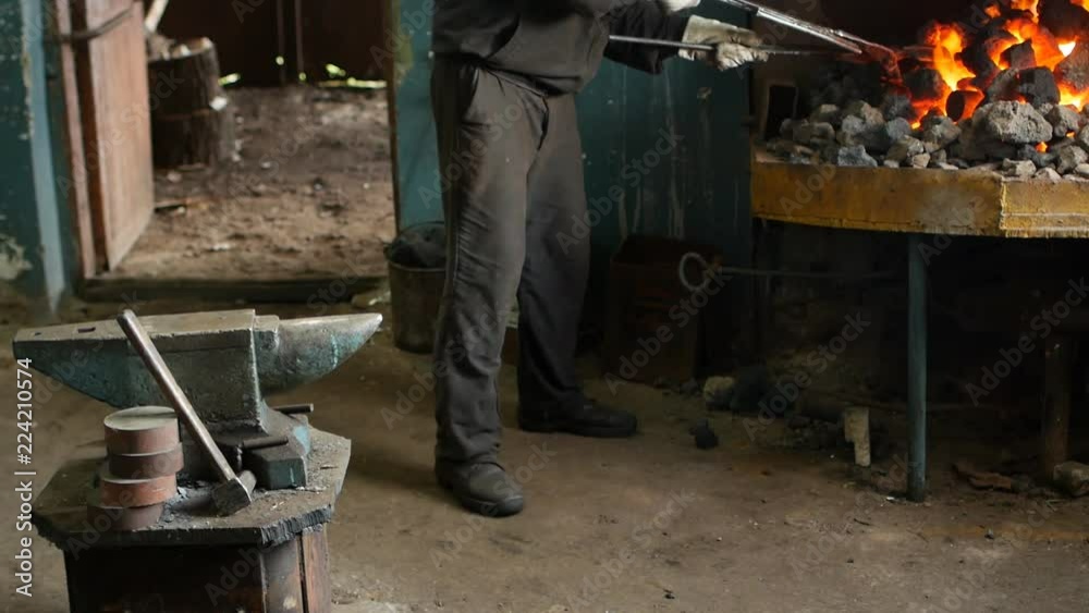 A blacksmith inverts the red-hot metal parts in the furnace, heat ...
