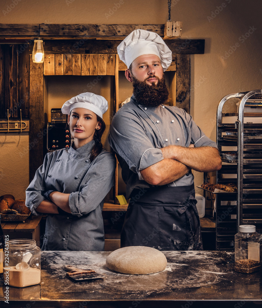 Chef with his assistant in cook uniform posing with crossed arms near ...