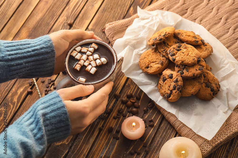 Woman taking cup of hot chocolate with marshmallows from wooden table ...