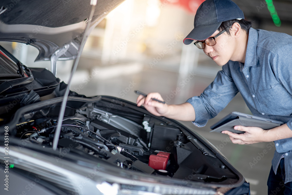 Asian auto mechanic holding digital tablet checking car engine under ...