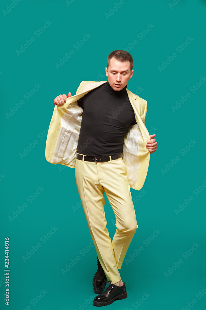 Attractive young man in suit dancing, having fun on mint background ...
