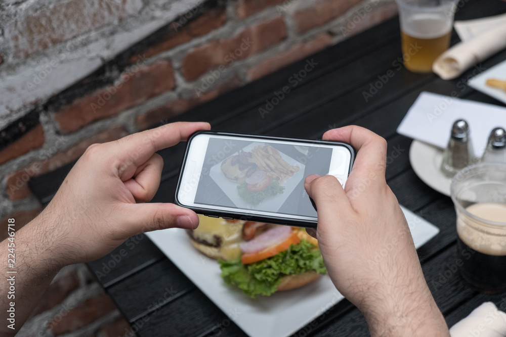 Point of view shot, man takes photo of food with mobile phone at an ...