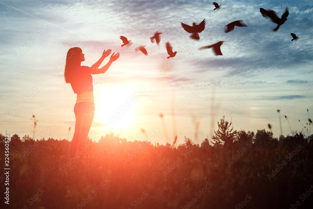 A young girl prays while enjoying nature amidst a beautiful sunset. The ...