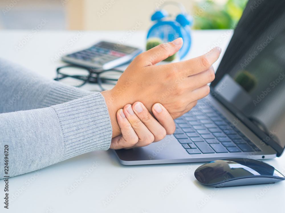 Closeup woman holding her wrist pain from using computer long time ...