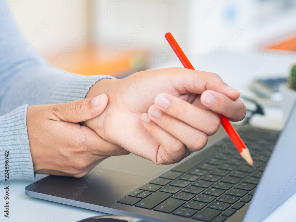 Closeup woman holding her wrist pain from using computer long time ...