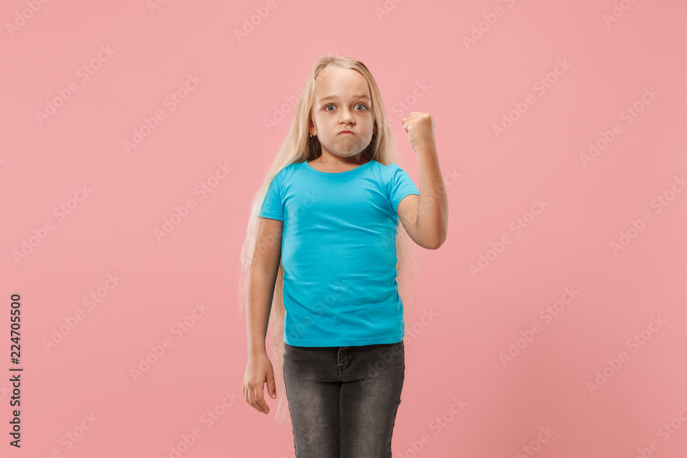 Angry teen girl standing on trendy pink studio background. Female half ...