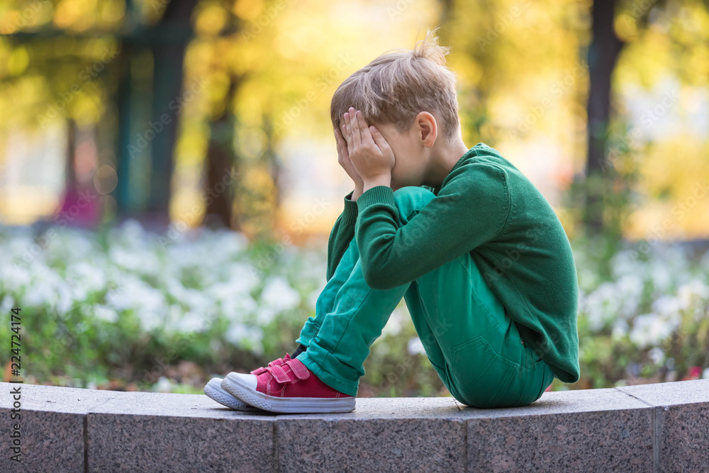Lonely, upset and sad Caucasian boy in green jeans and sweater, in red ...