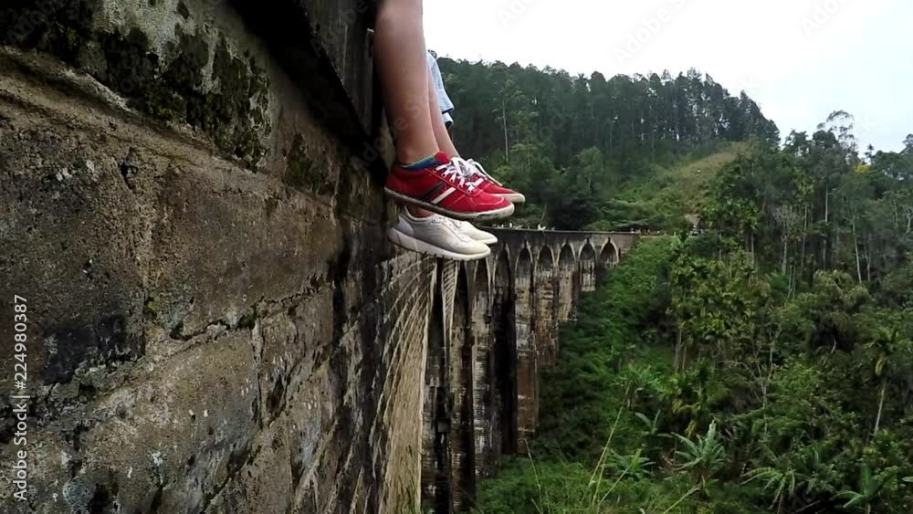 4K footage of people hanging their feet from the viaduct and dangling ...
