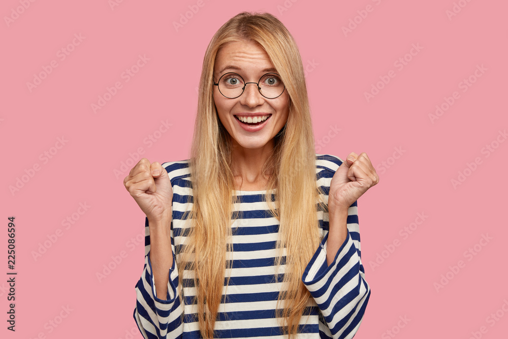 Overjoyed European young woman with broad smile, clenches teeth, looks ...