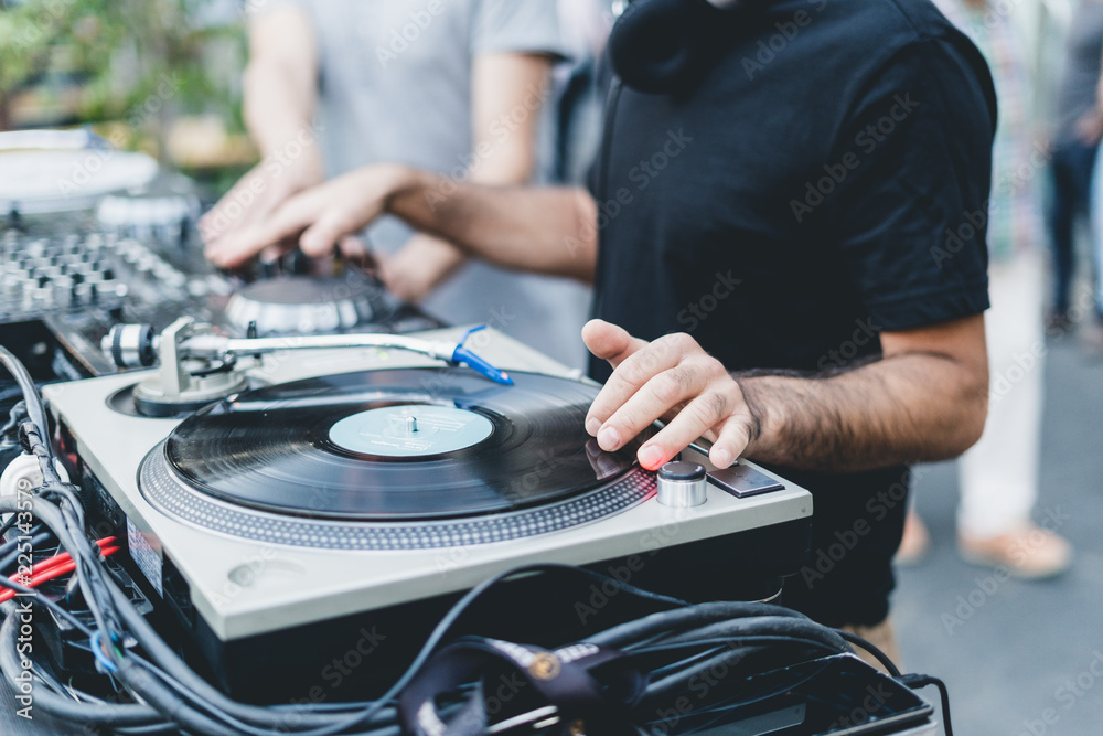 DJ mixing vinyl records on a turntable in a daily outdoor party. Focus ...