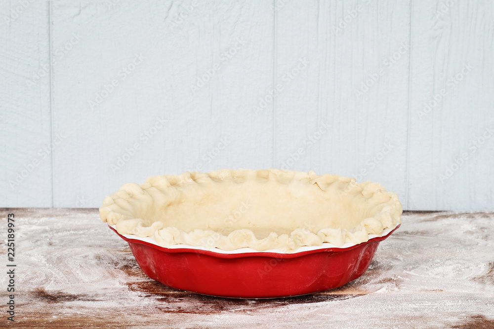 Homemade butter pie crust in pie plate with fluted pinched edge against ...
