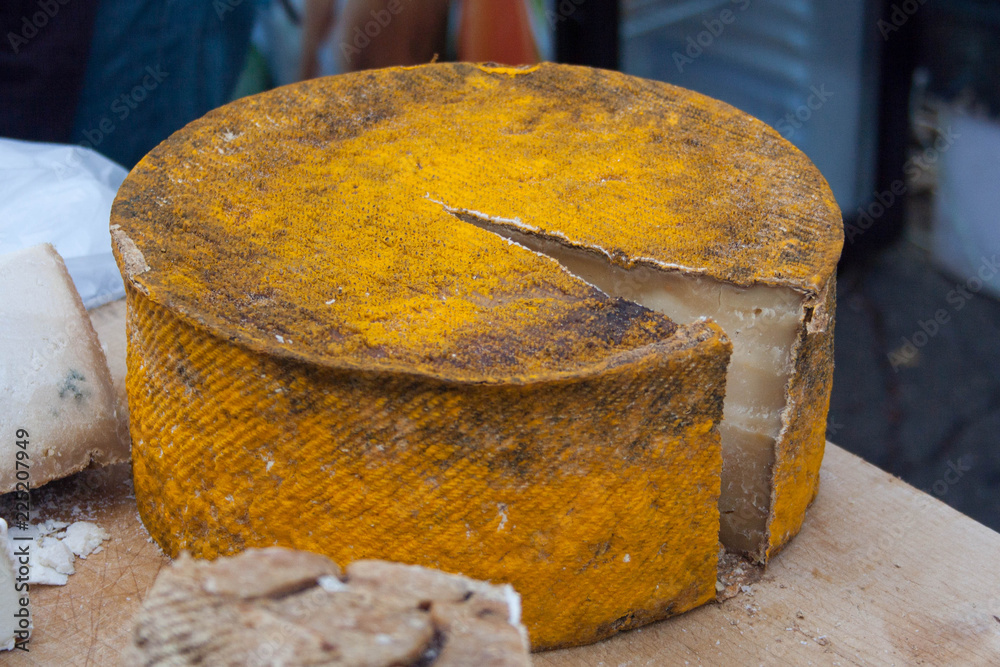 Old and spicy parmesan type firm cheese wheel with cut out triangle ...