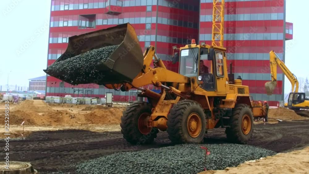 Wheel loader working on construction site. Bulldozer unloads crushed ...