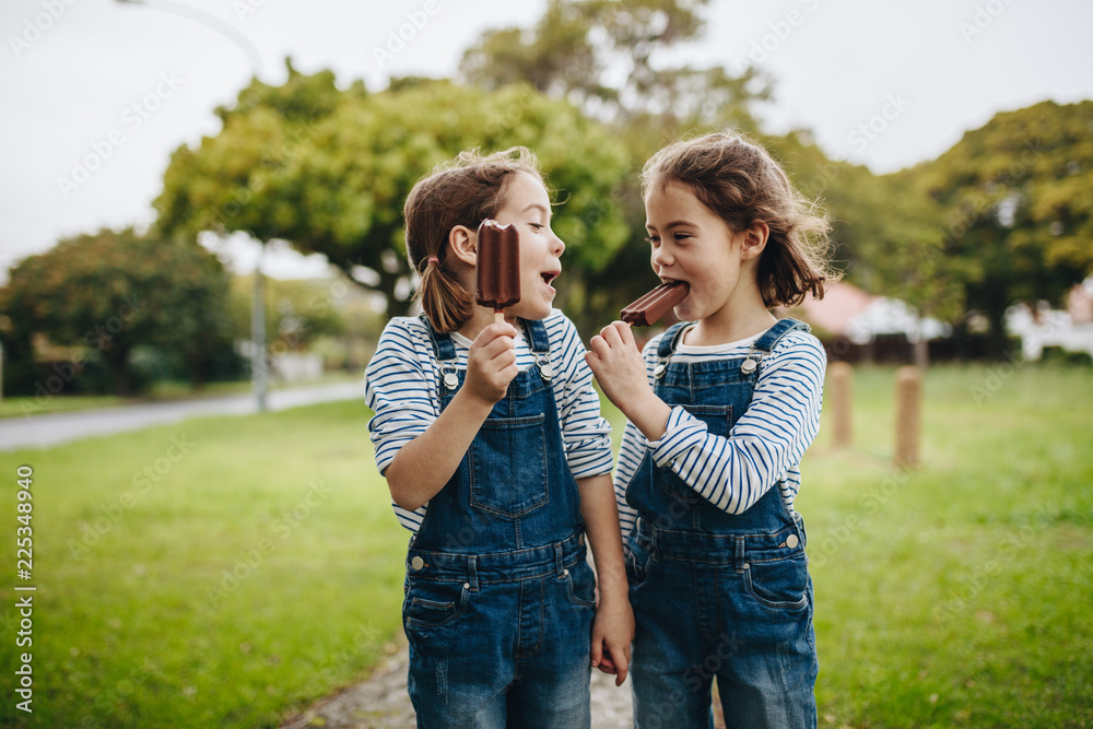 Twin sisters enjoying eating candy icecream Stock Photo | Adobe Stock