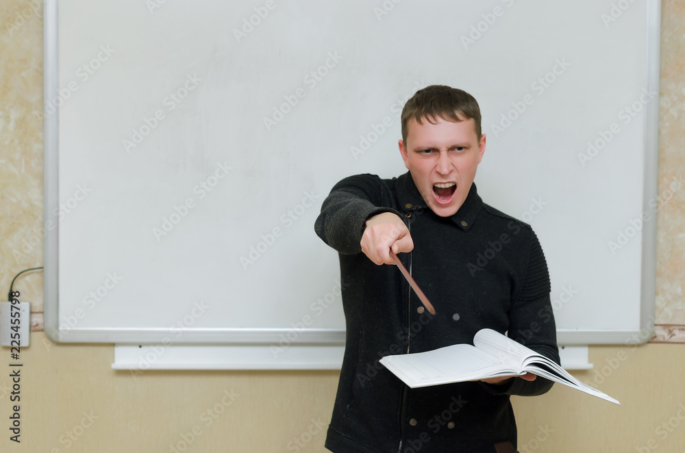 Angry teacher with class book is standing by the blackboard and ...