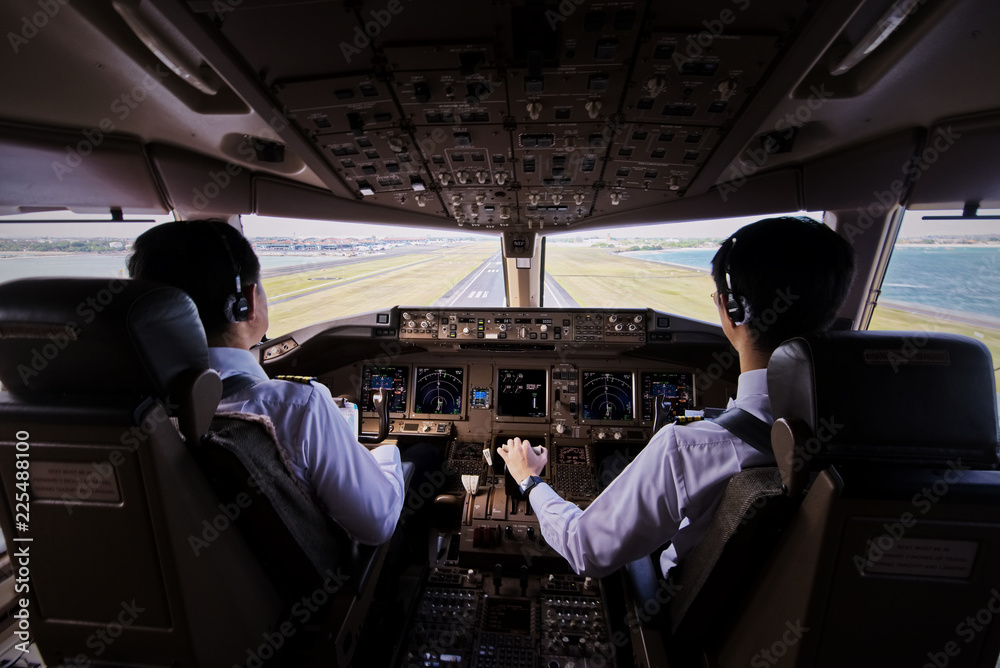 Two airliner pilots are flying the airplane towards the runway. Outside ...