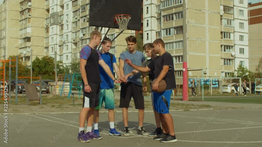 Vidéo Stock Teenage basketball team stacking hands on court before ...