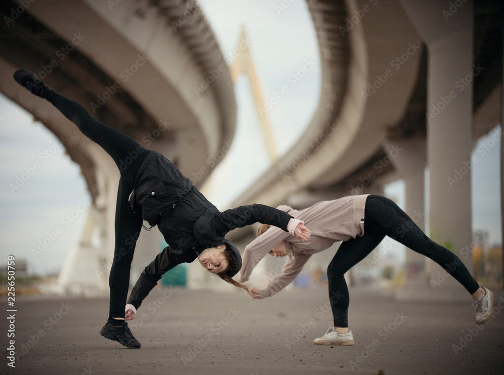 Girls begin to perform a synchronized jump in the splits on the urban ...
