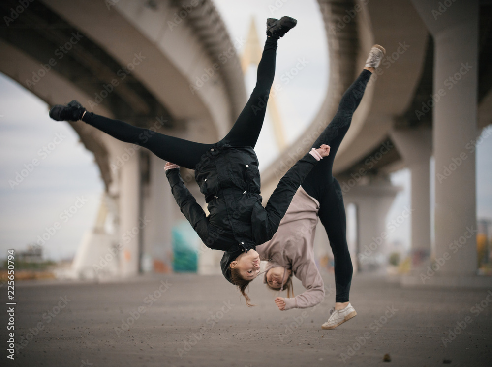 Girls perform splits in the air while jumping on the urban background ...