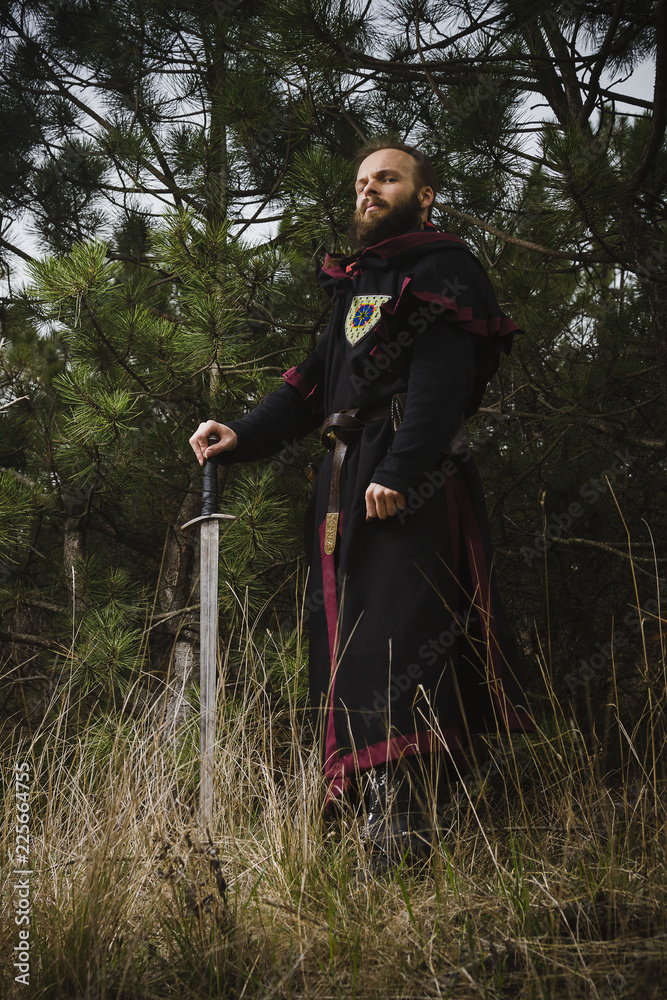 a medieval knight stands leaning on a sword Stock Photo | Adobe Stock