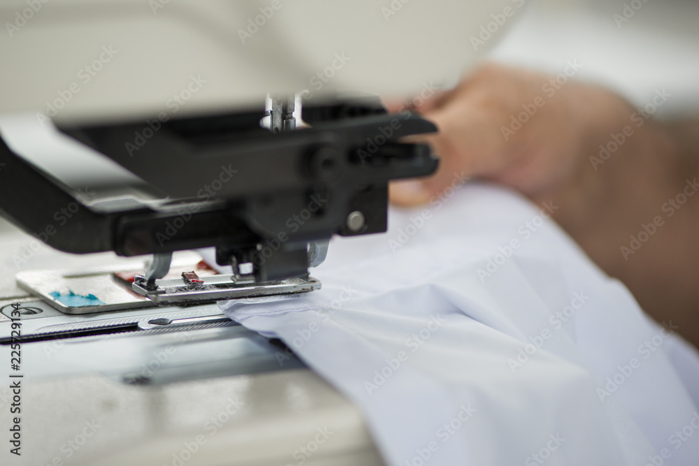 seamstress male on a sewing machine makes a shirt in the sewing ...