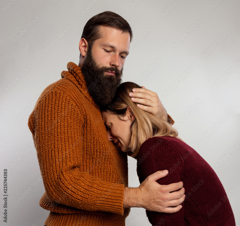 Bearded handsome man hugging his sad girlfriend, beautiful woman is ...