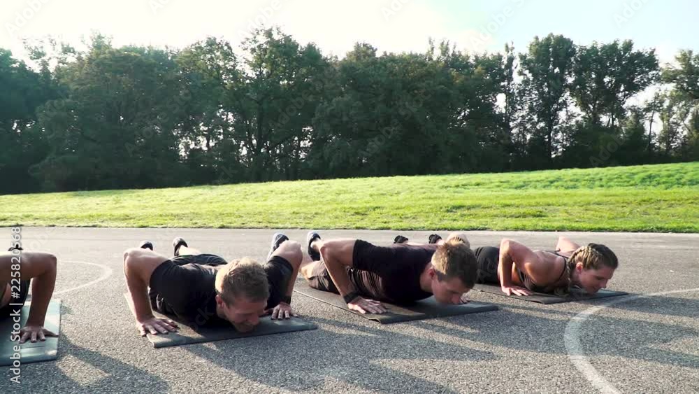two girls and two boys doing 6 count burpees outdoor in the morning sun ...