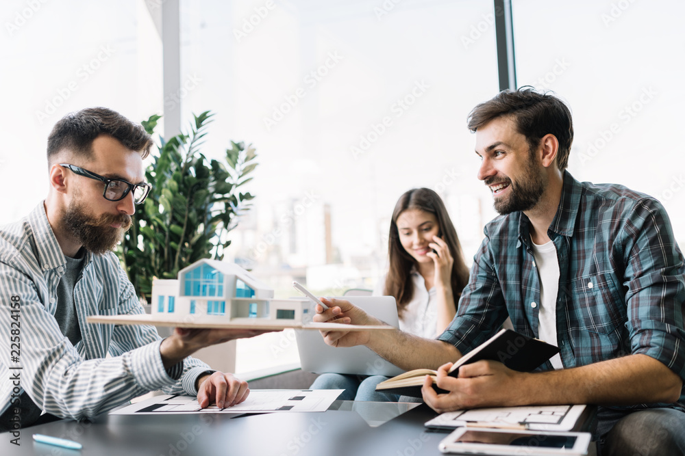 Fotka „Architects working with model house and blueprints. Teamwork ...