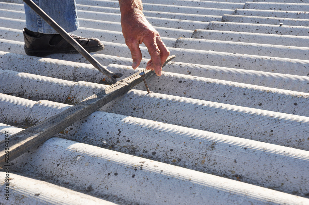 Pull out the nails from asbestos old roof tiles. Roof worker repair and ...