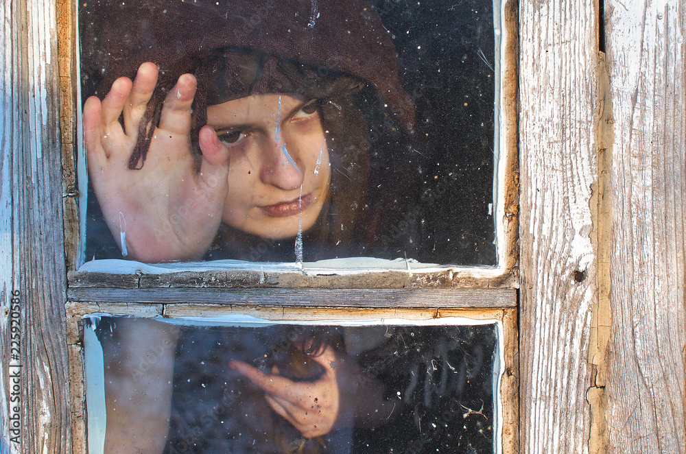 sad woman with bruises under her eyes, wrapped in wool, looks sadly at ...
