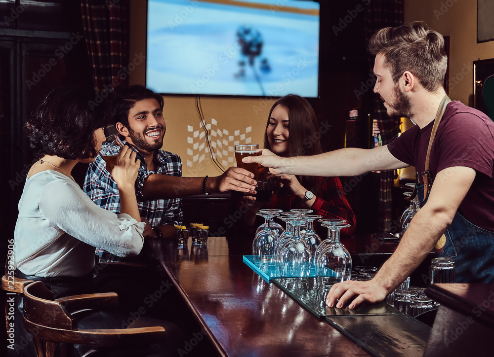 Young multiracial friends in bar. barman giving glass of beer to ...