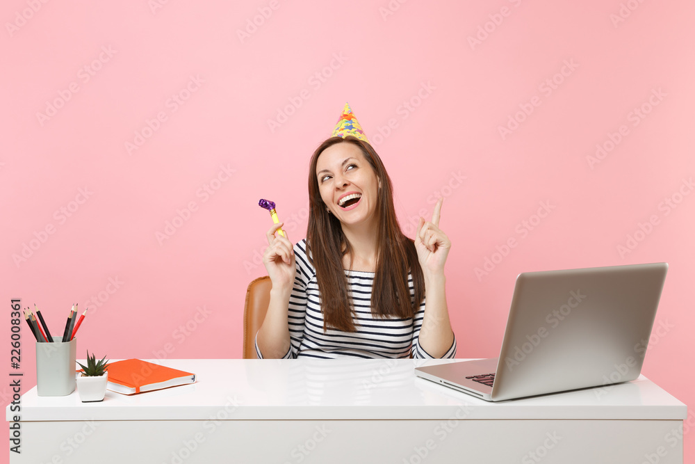 Laughing woman in birthday party hat with playing pipe celebrating ...