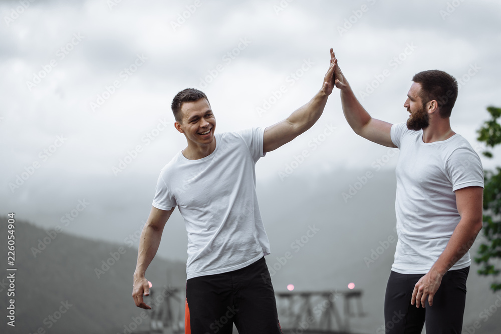 Two male athletes clasping hands together in high five gesture over ...