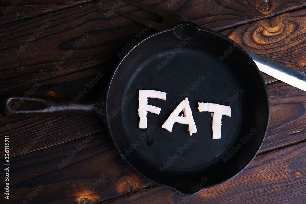 Frying pan with word Fat carved of bacon. Unhealthy food, overweight ...