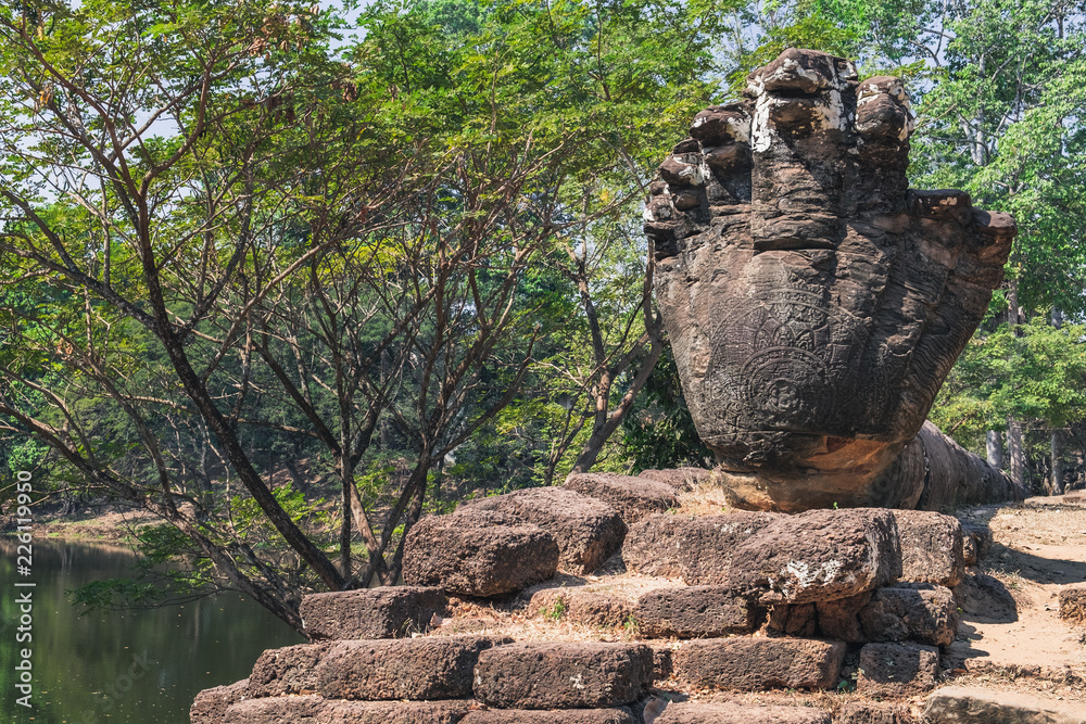 Statue of Naga near Prasat Bakong temple is surrounded by tropical ...