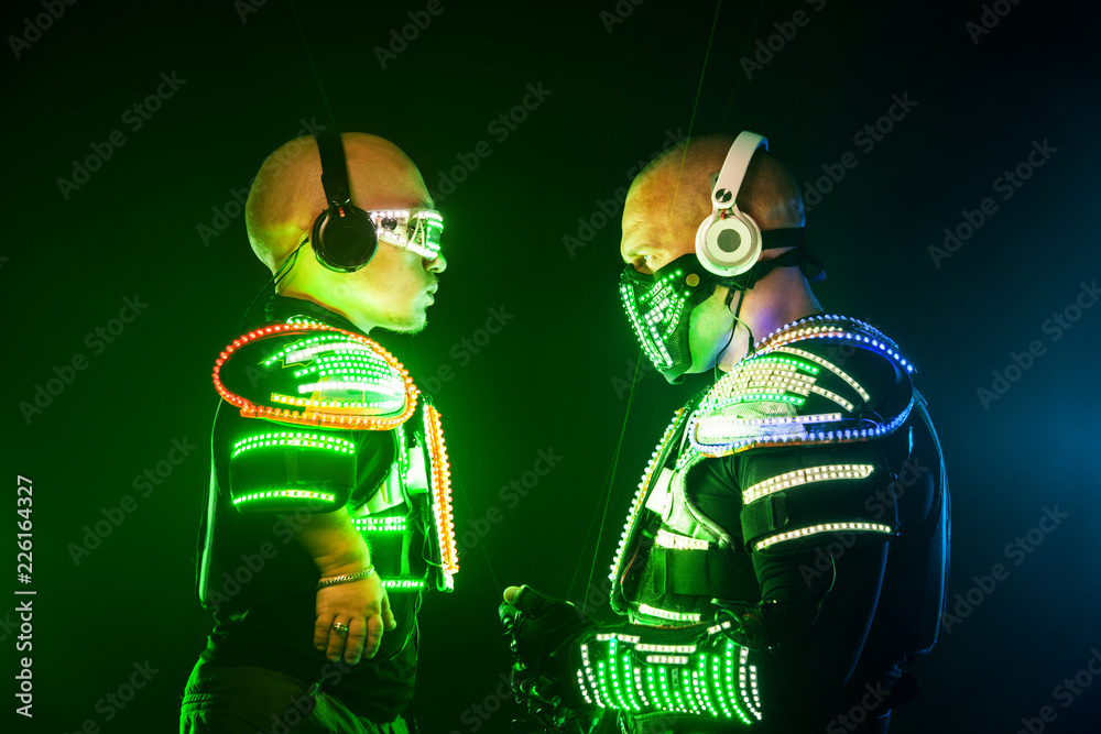 Mysterious man and midget in black wear, neon mask and gloves ...